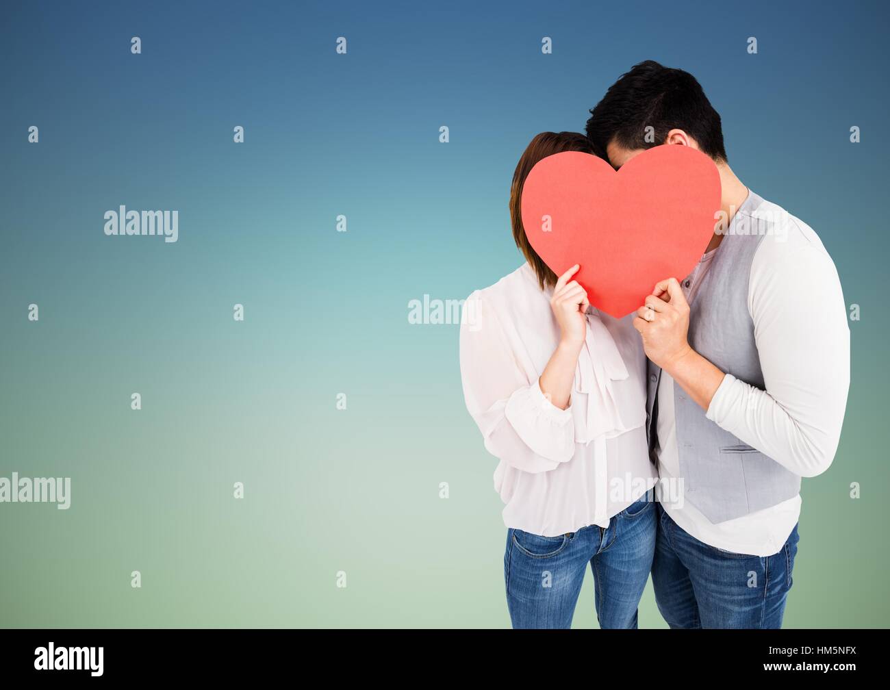 Couple hiding their face behind red heart Stock Photo - Alamy