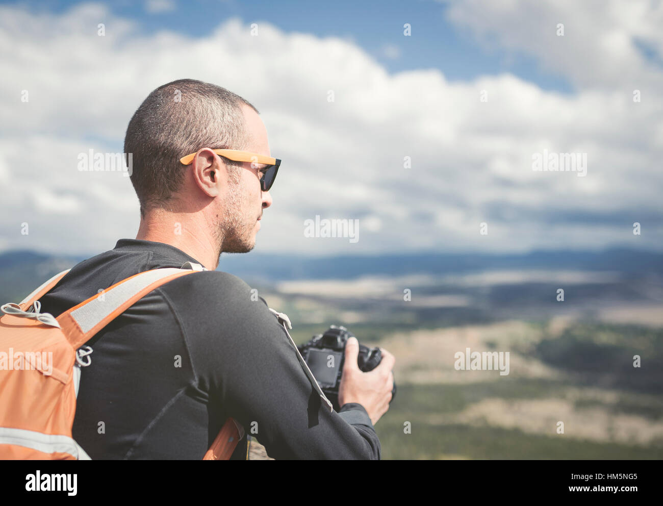 Hiker holding camera while looking at landscape Stock Photo - Alamy