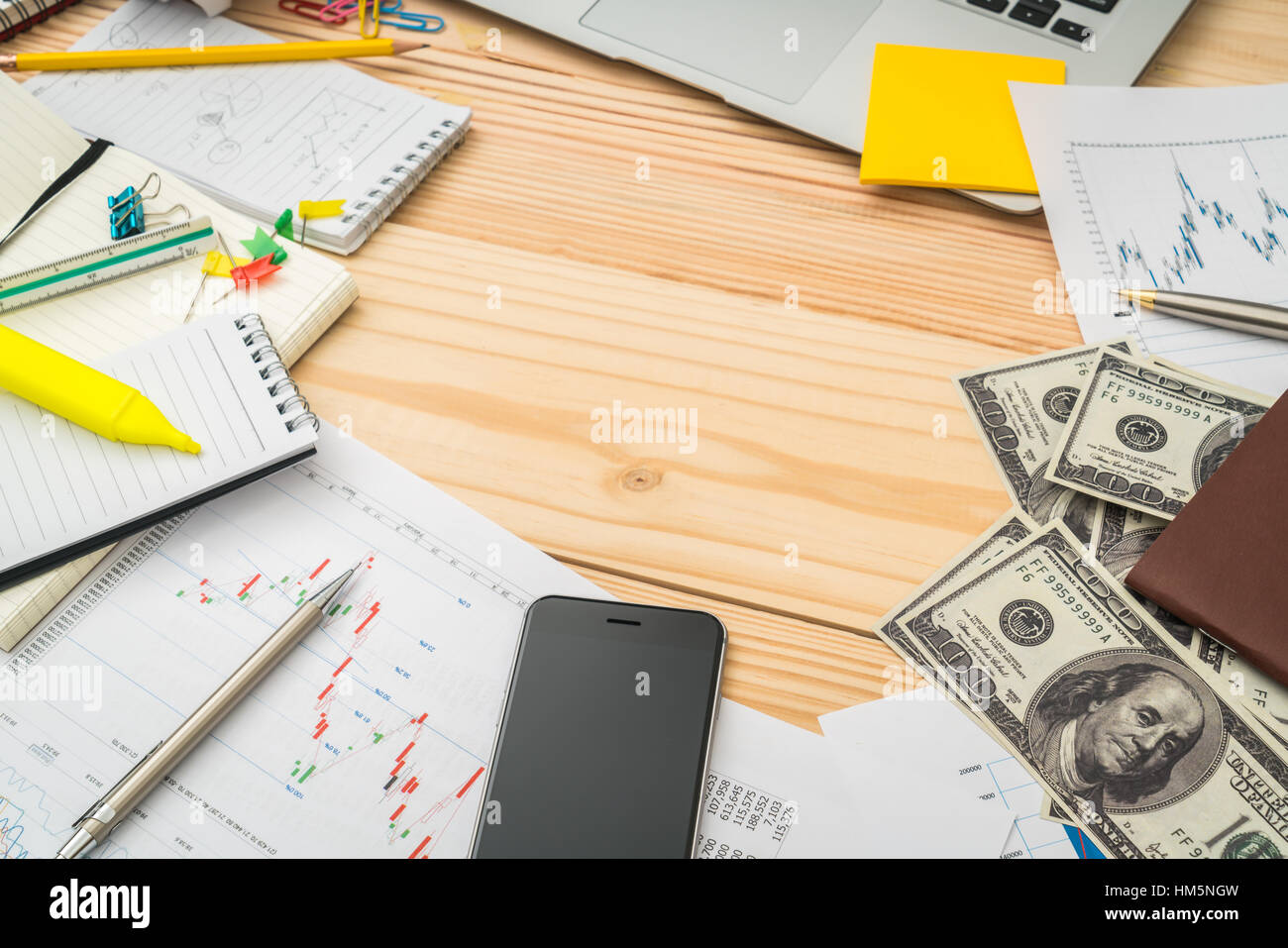 Financial charts on the table with laptop , phone ,dollars banknotes ...
