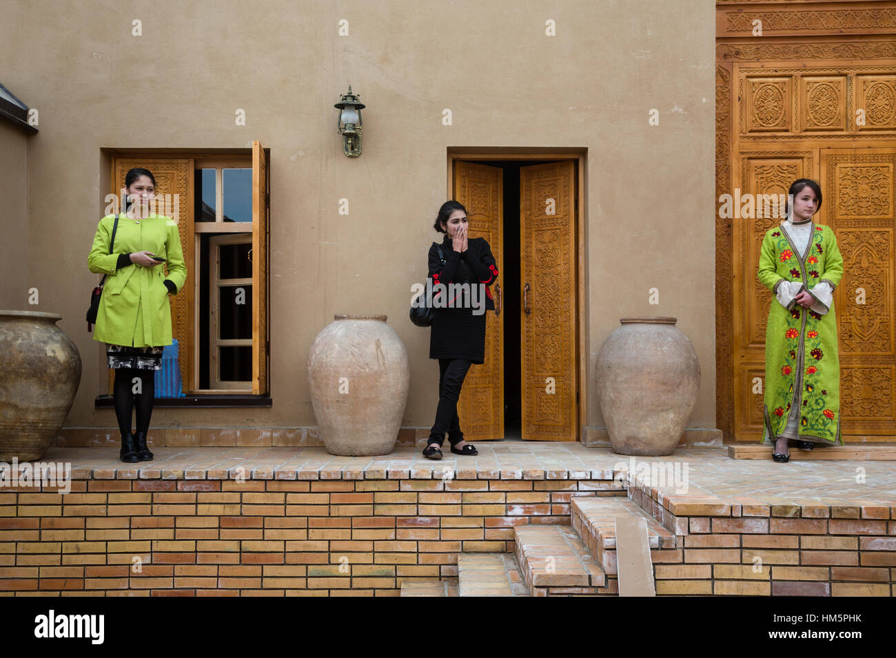 Tajik young girls standing at the entrance to a house with a door ...