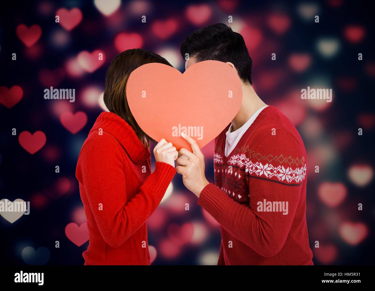 Romantic couple hiding their face behind heart Stock Photo - Alamy