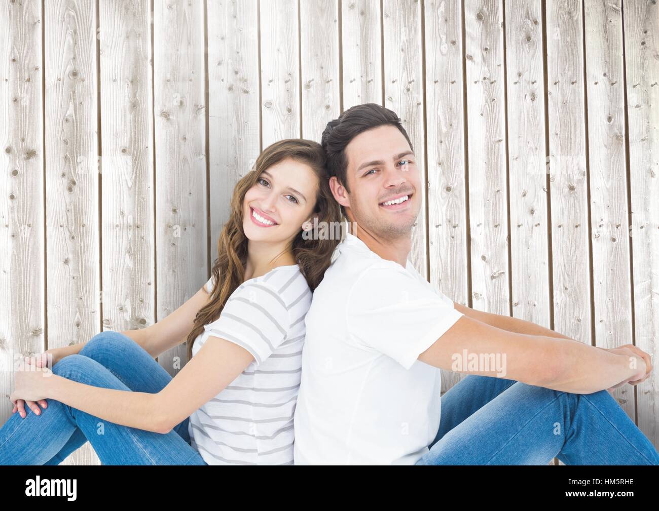 Happy couple sitting back to back Stock Photo - Alamy