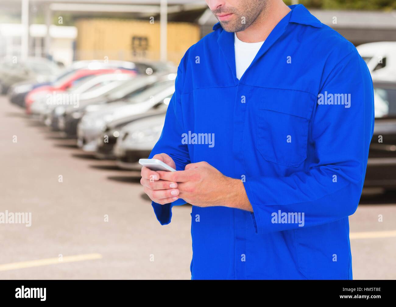 Car mechanic using mobile phone against car parked Stock Photo - Alamy
