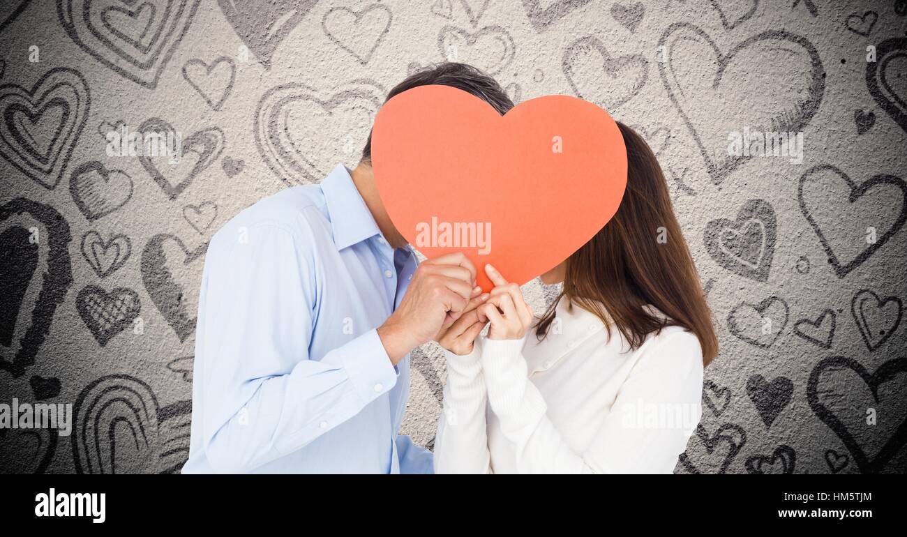 Romantic couple hiding their face behind red heart Stock Photo - Alamy