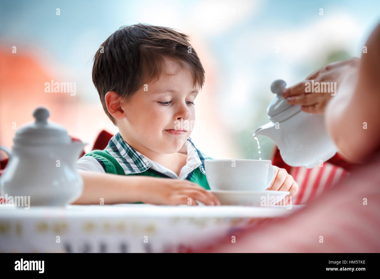 Cute little boy drinking tea in cafe Stock Photo - Alamy