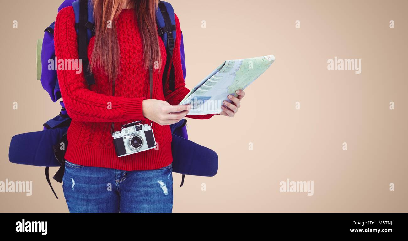 Mid section of woman with digital camera and backpack reading newspaper ...