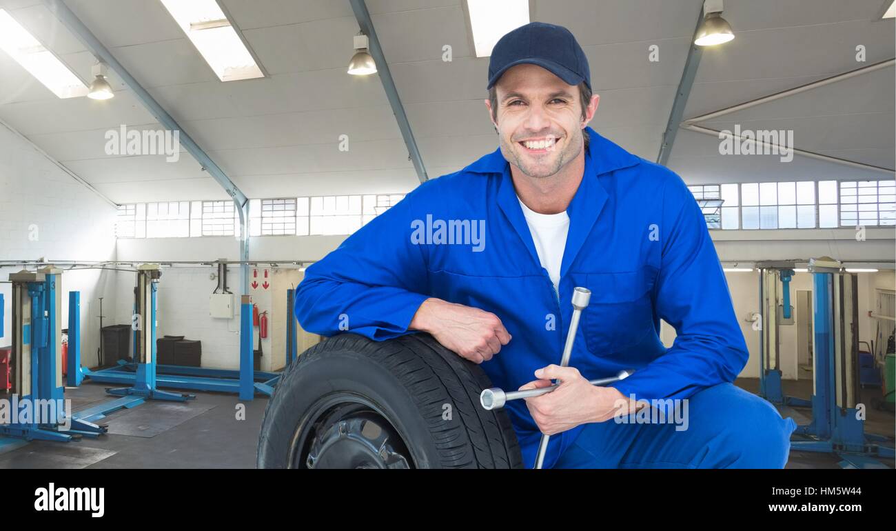 Smiling mechanic leaning on the tire Stock Photo - Alamy