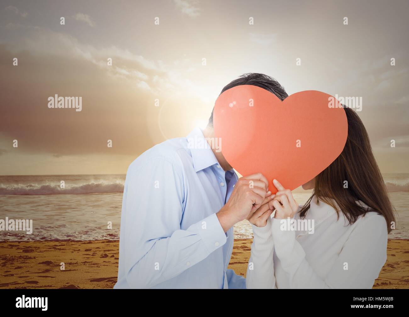 Romantic couple hiding their face behind red heart Stock Photo - Alamy