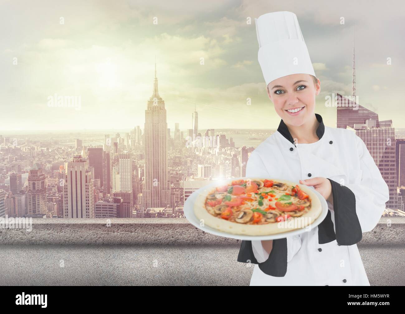 Happy female chef with pizza against skyline Stock Photo - Alamy