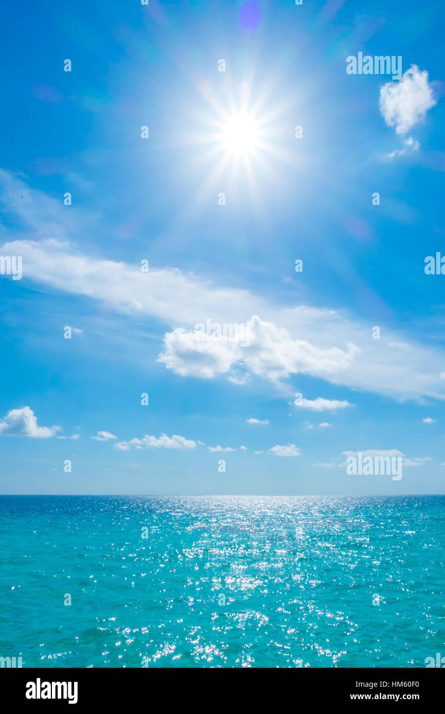 White clouds with blue sky and sun over calm sea in tropical Maldives ...