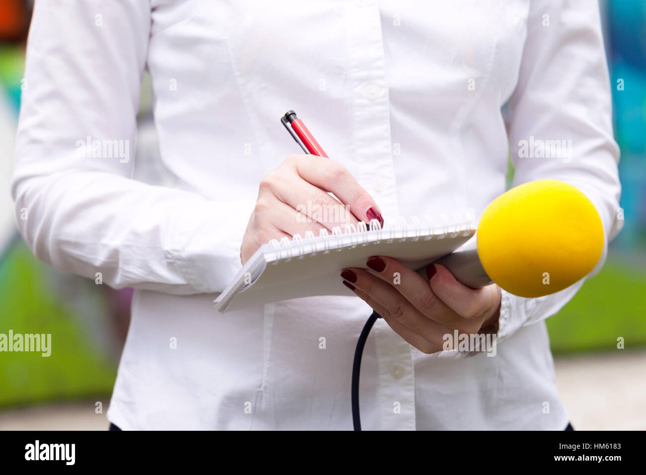 Female reporter at press conference, writing notes, holding microphone ...
