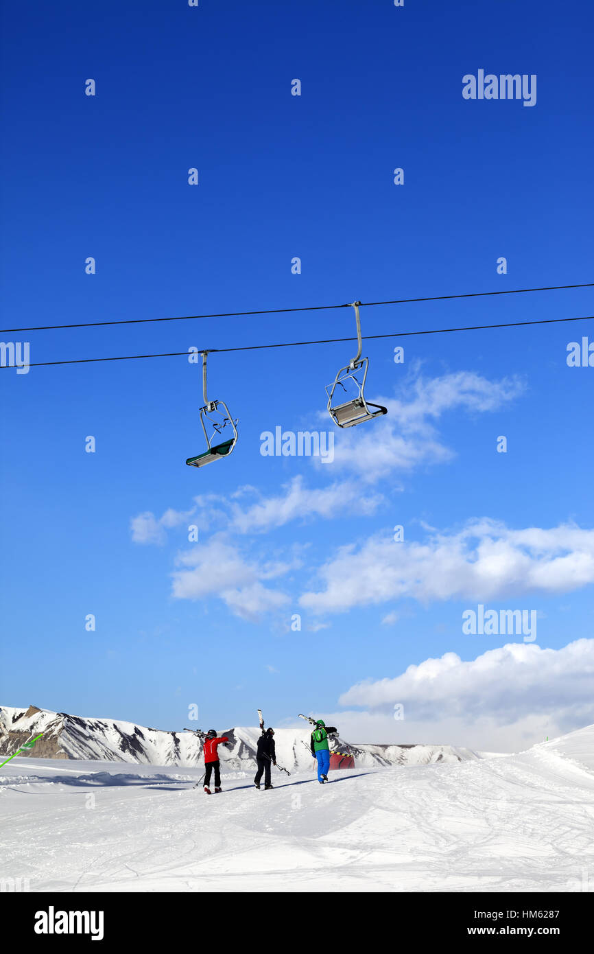 Three skiers on slope at sun winter day. Greater Caucasus, Mount ...