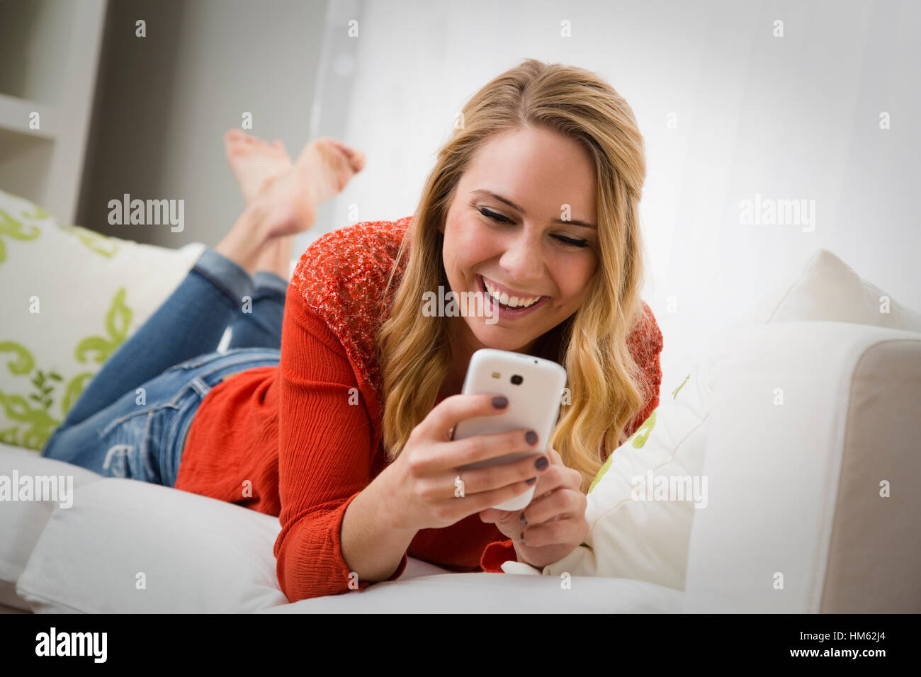 Young woman texting on sofa Stock Photo - Alamy
