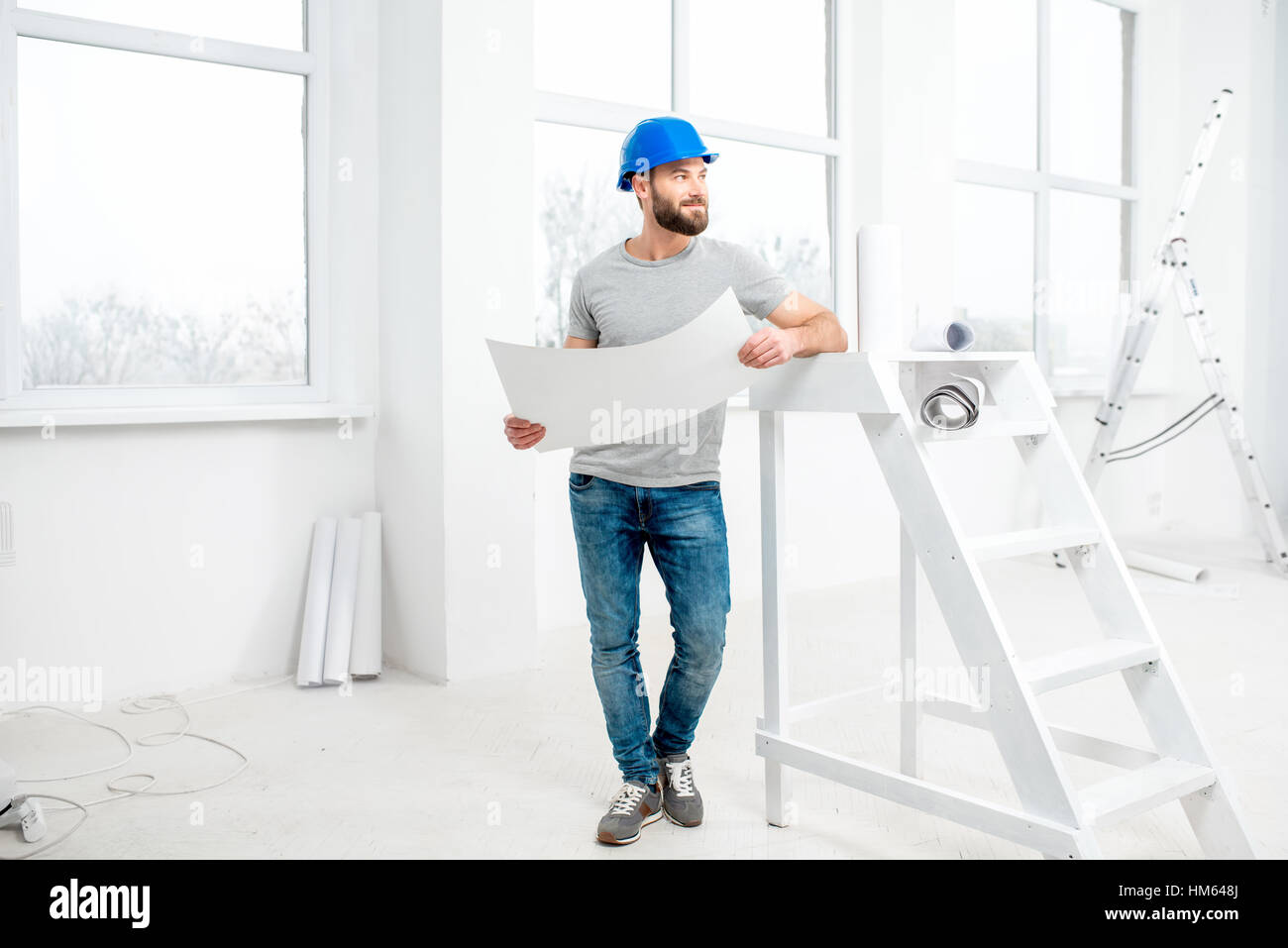 Handsome repairman or builder in helmet working with drawings on ...