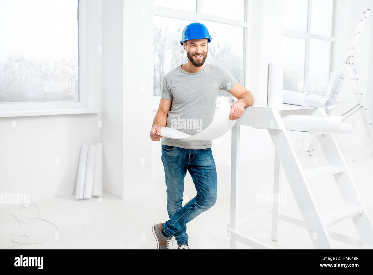 Handsome repairman or builder in helmet working with drawings on ...
