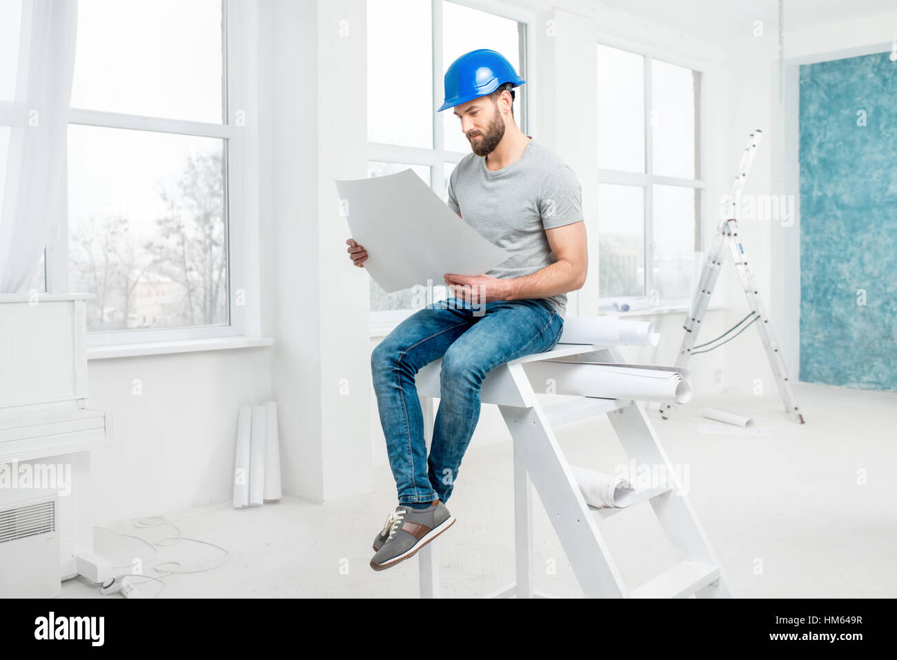 Handsome repairman or builder in helmet working with drawings on ...