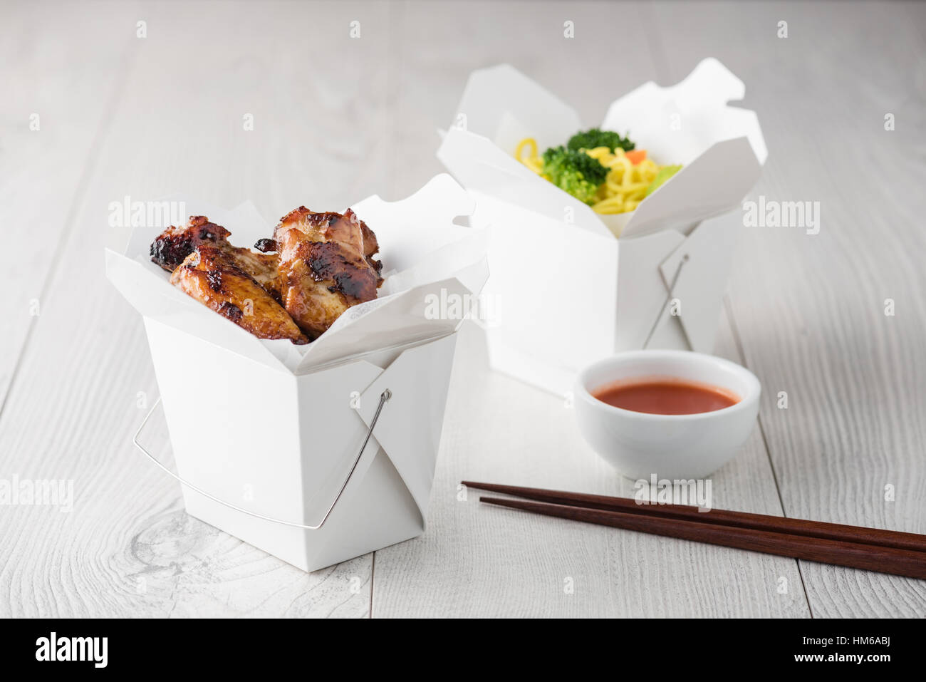 Asian chicken wings and noodles in take-out box with dipping sauce ...
