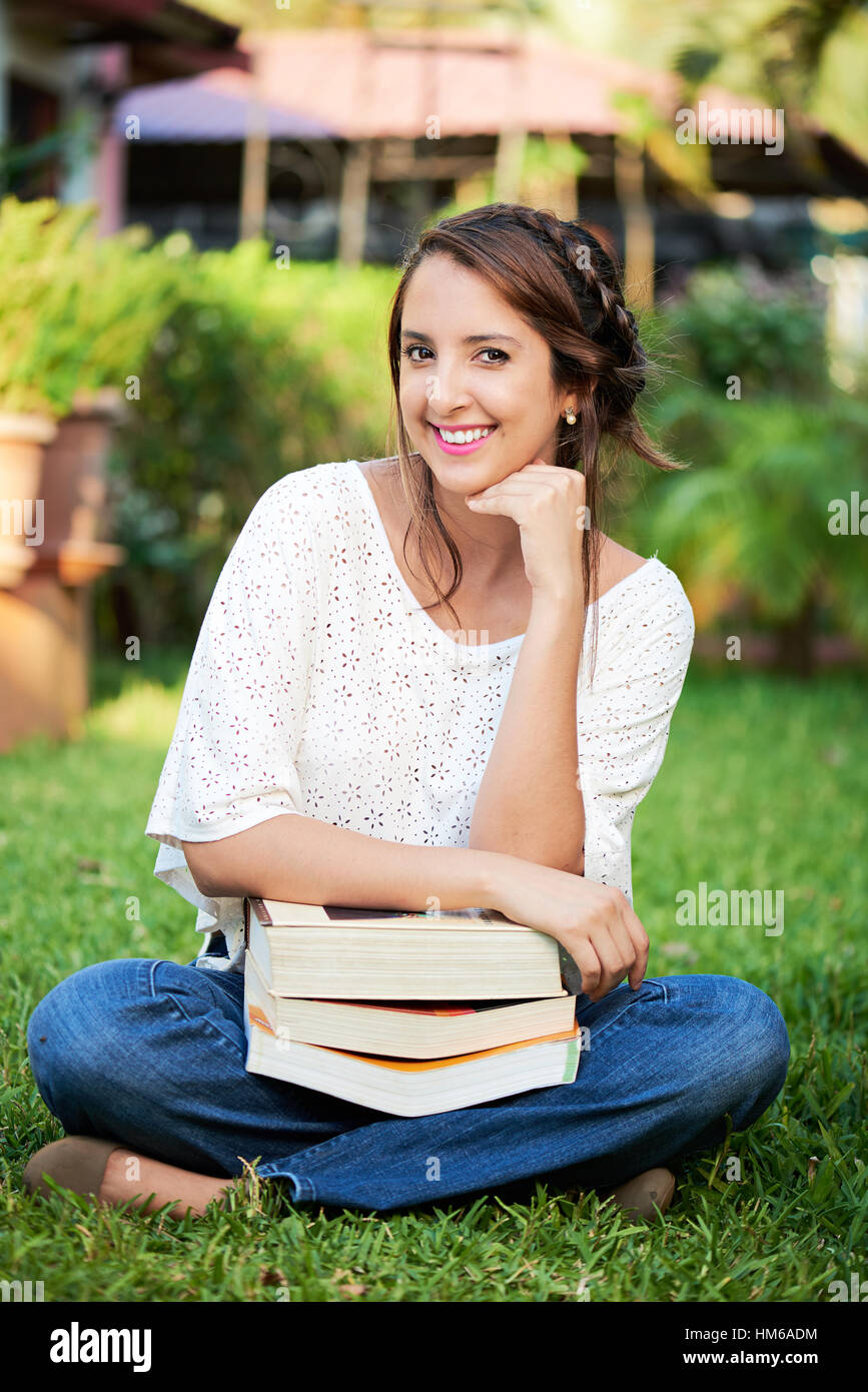 smiling girl with books sit on grass in park Stock Photo - Alamy