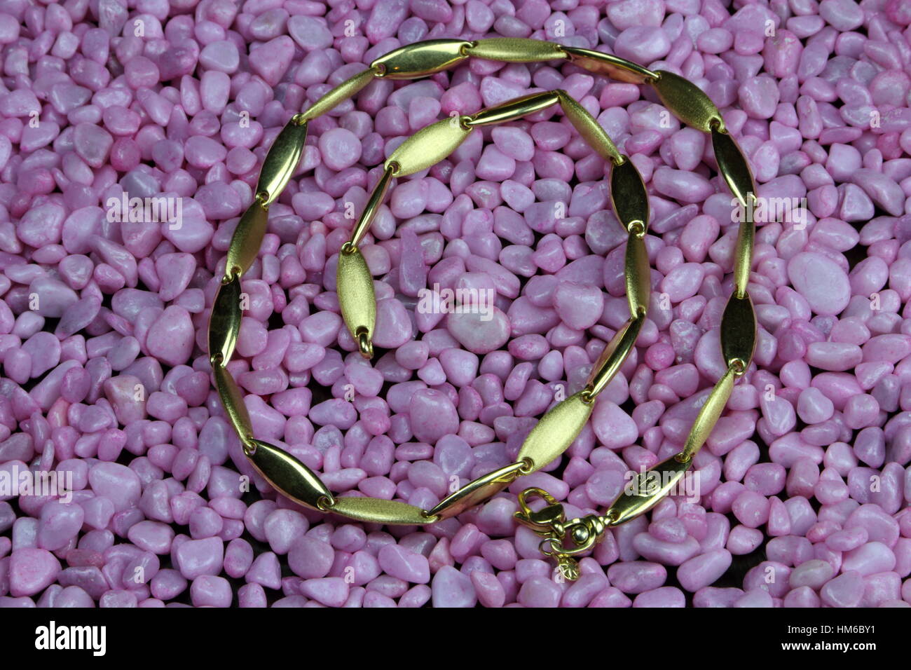 Gold necklace on pink pebbles - Jewelry on colorful pebbles indoor ...