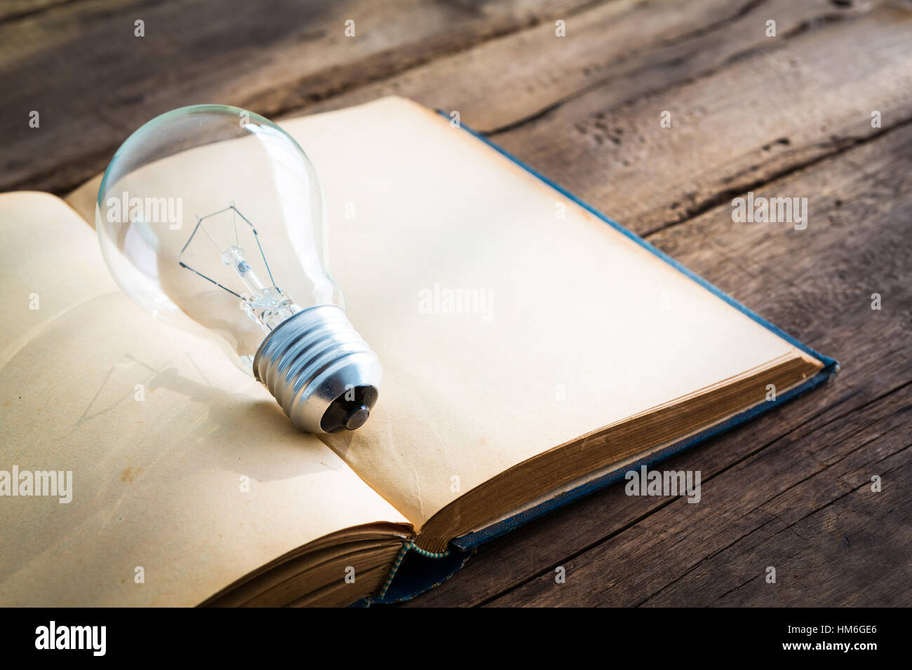 vintage book and light bulb on wood table Stock Photo - Alamy