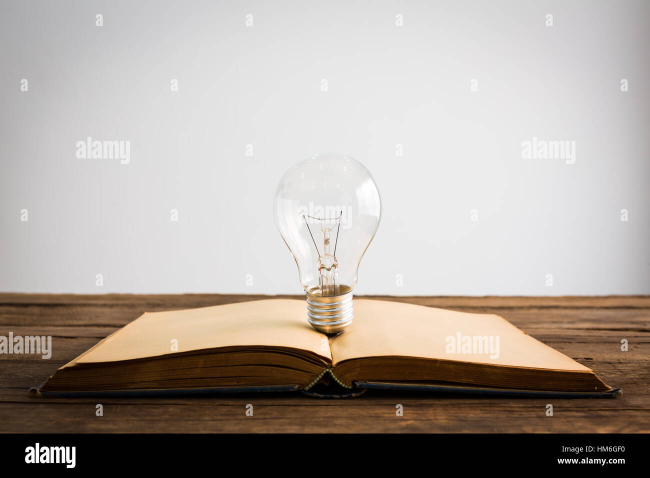 vintage book and light bulb on wood table Stock Photo - Alamy