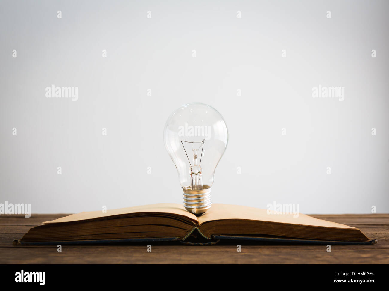 vintage book and light bulb on wood table Stock Photo - Alamy