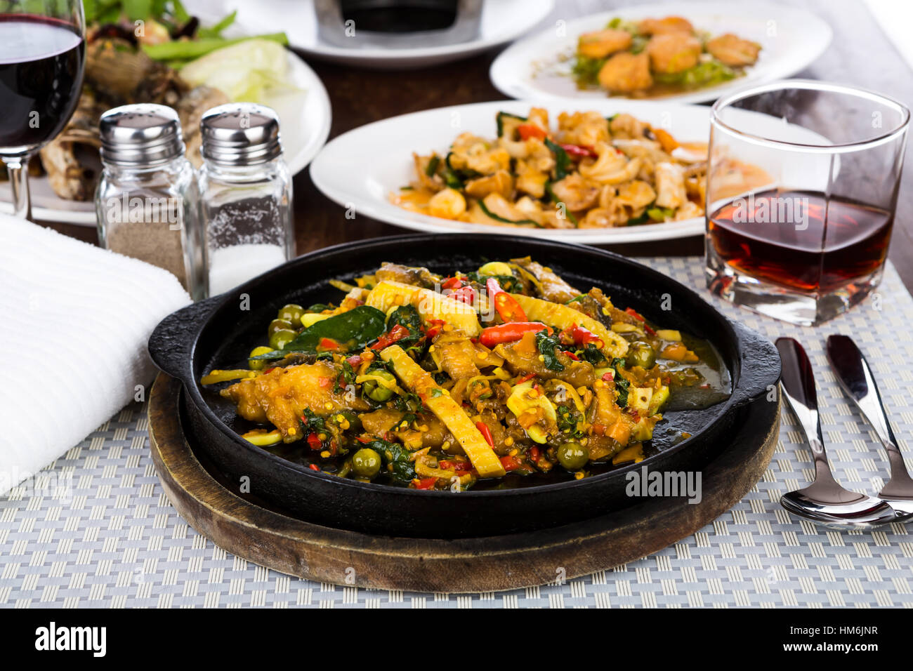 Fried fish with fresh herbs and spicy sauce served on iron hot plate ...