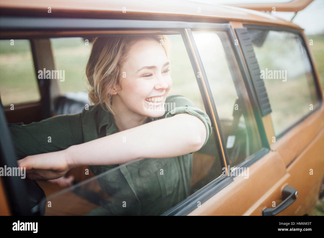 Woman leaning out of a car window and smiles Stock Photo - Alamy