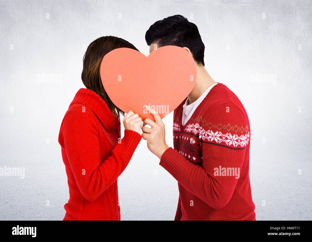 Romantic couple hiding their face behind heart Stock Photo - Alamy