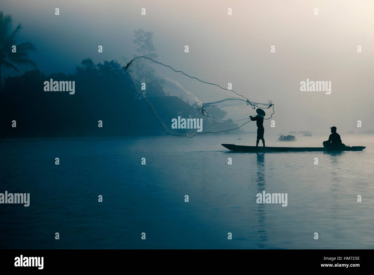 Fisherman casting out his fishing net early in the morning Stock Photo ...