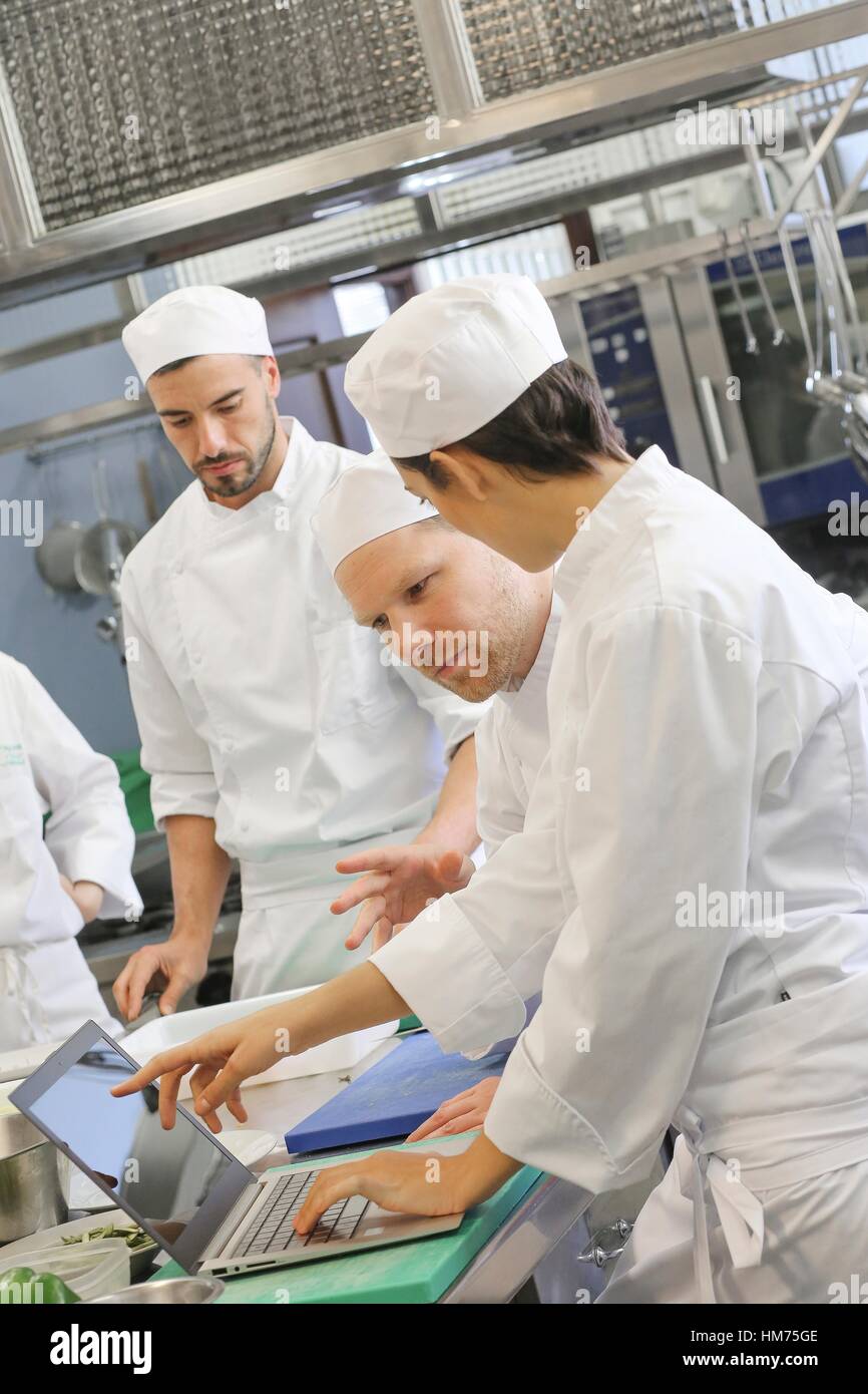 Chefs using computer in restaurant kitchen Stock Photo - Alamy