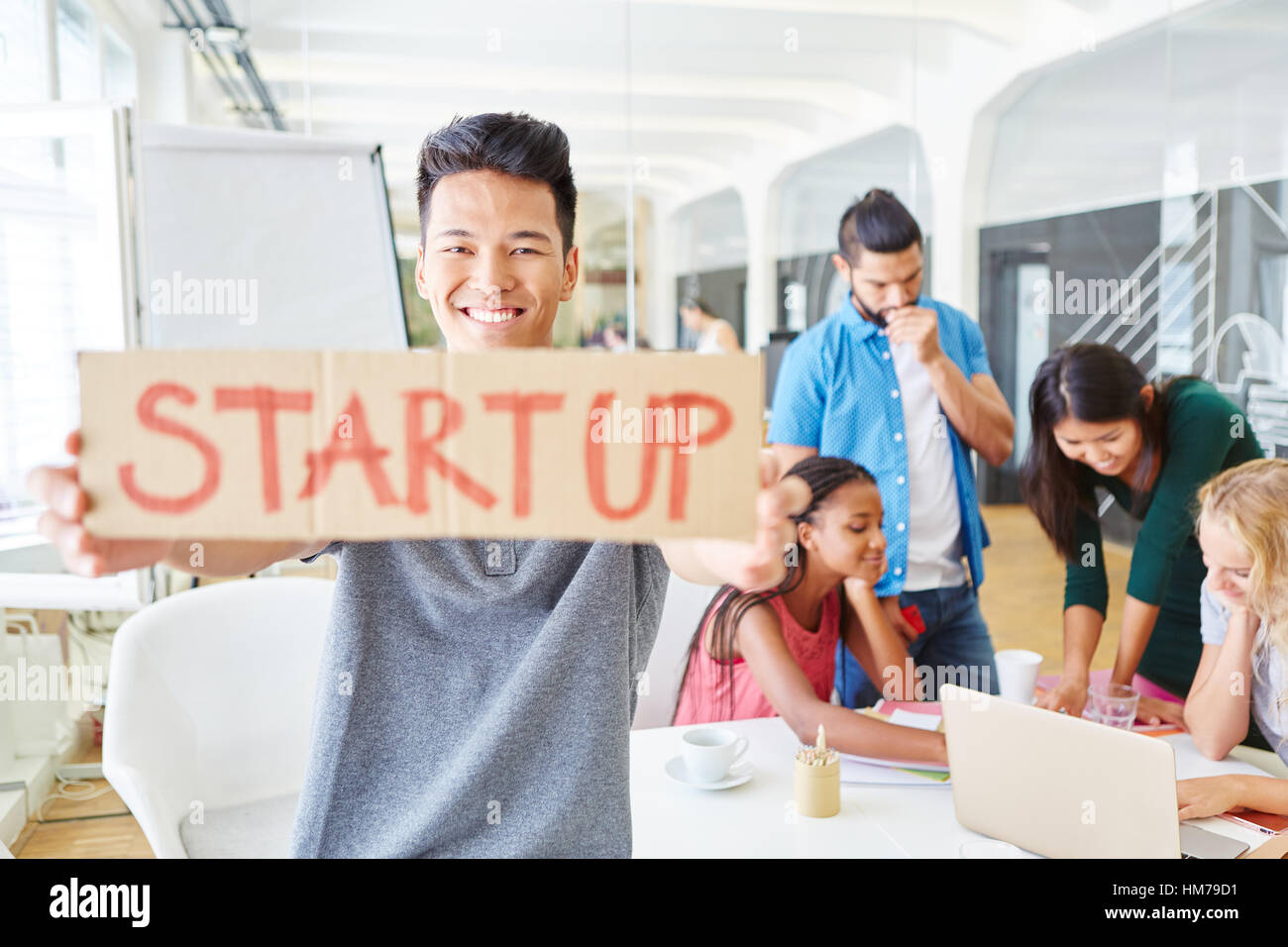 Start-up founder with business team holding sign Stock Photo - Alamy