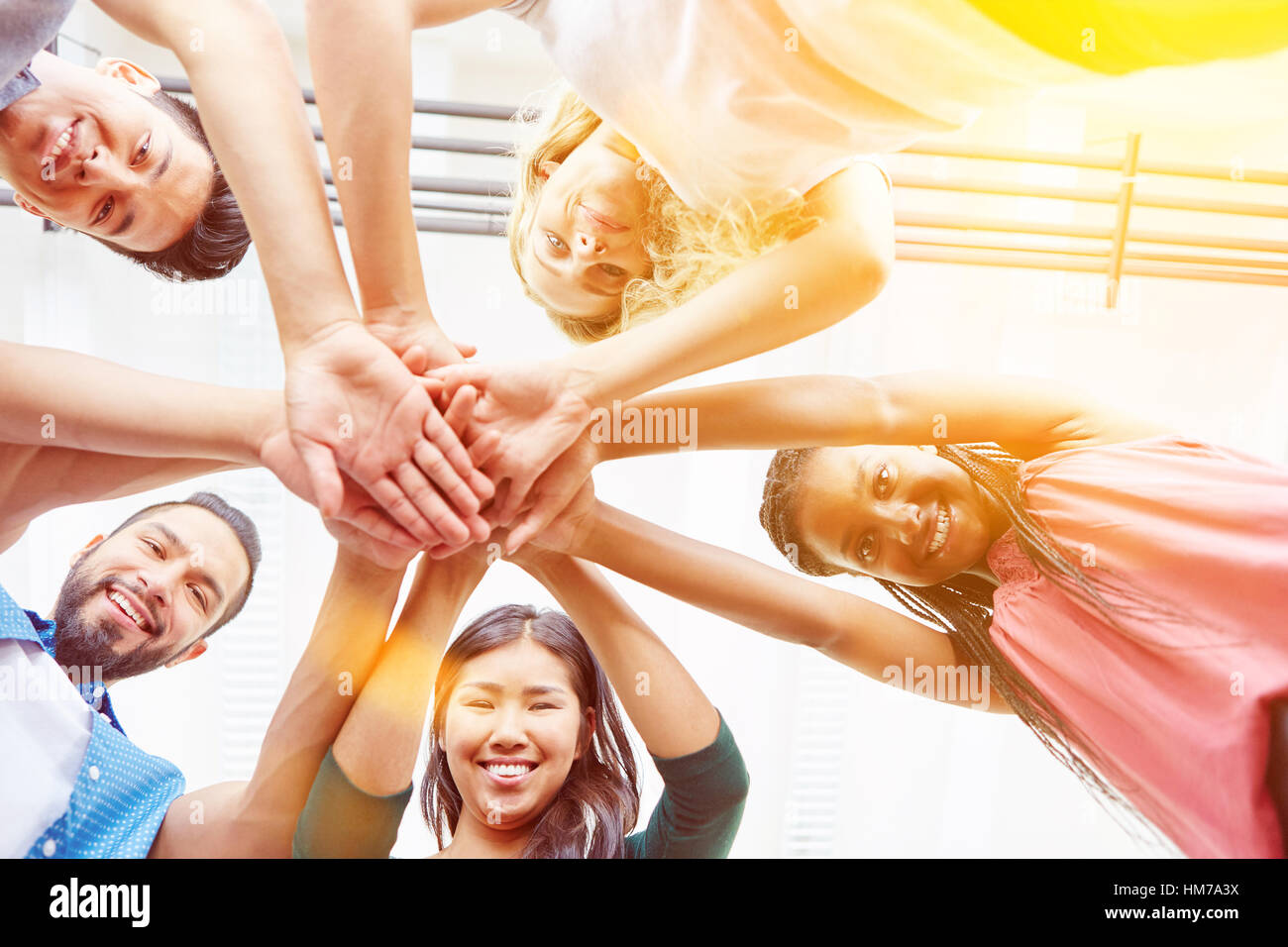 Students stacking their hands together as teamwork and motivation ...