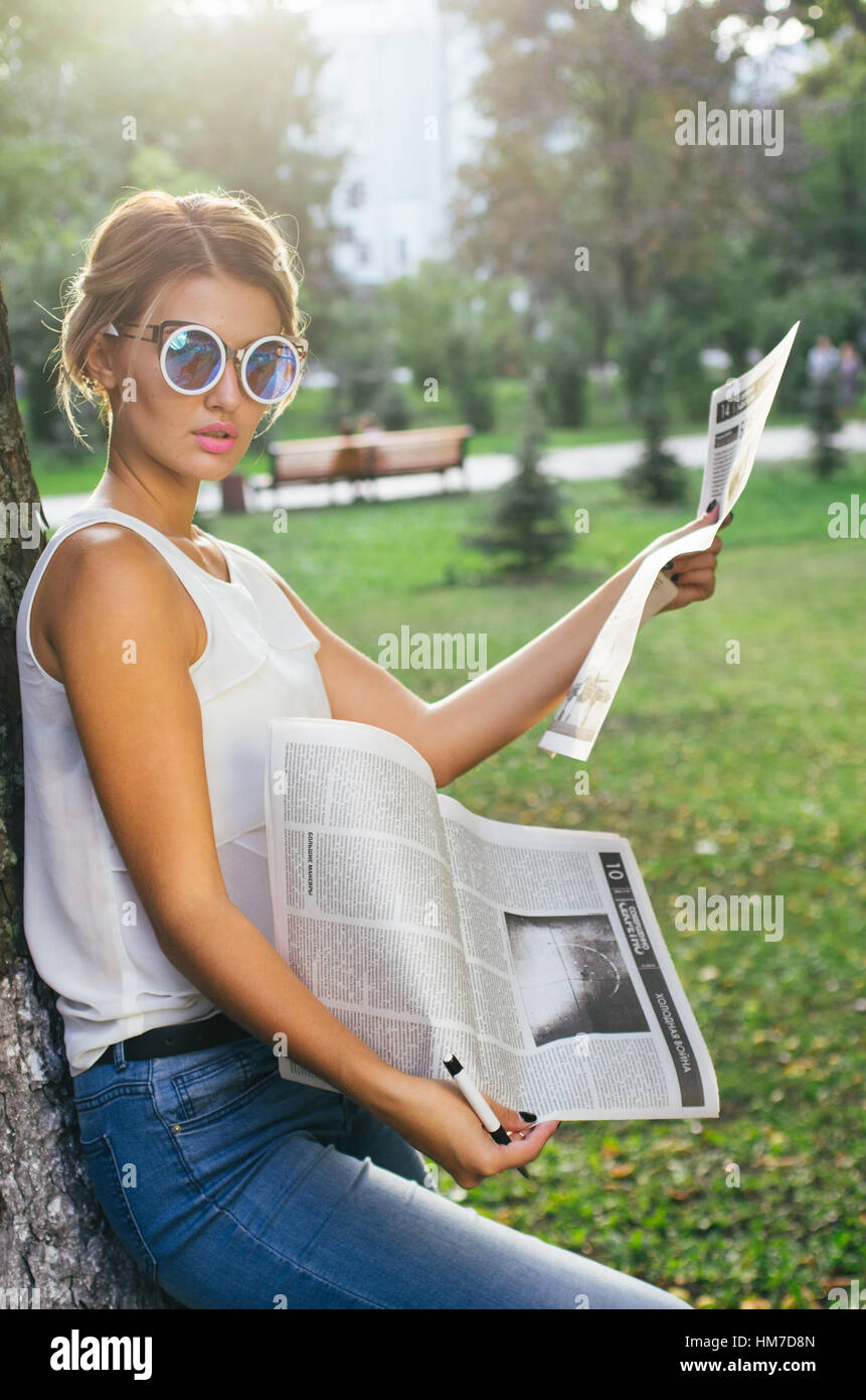 Gorgeous woman reading a magazine in the park Stock Photo - Alamy