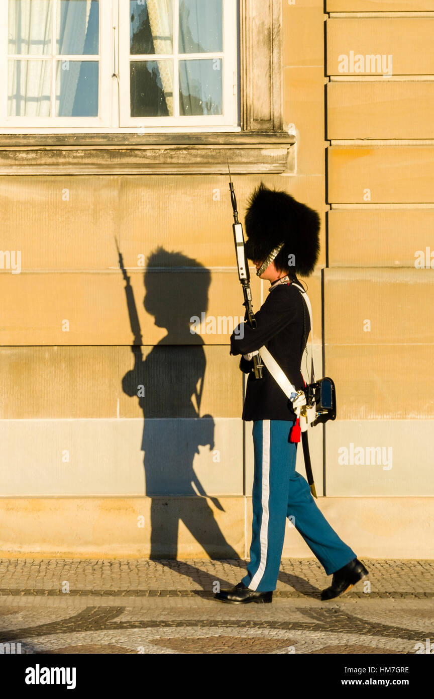 A member of the Royal Guard patrols the palace at sunset with a rifle ...