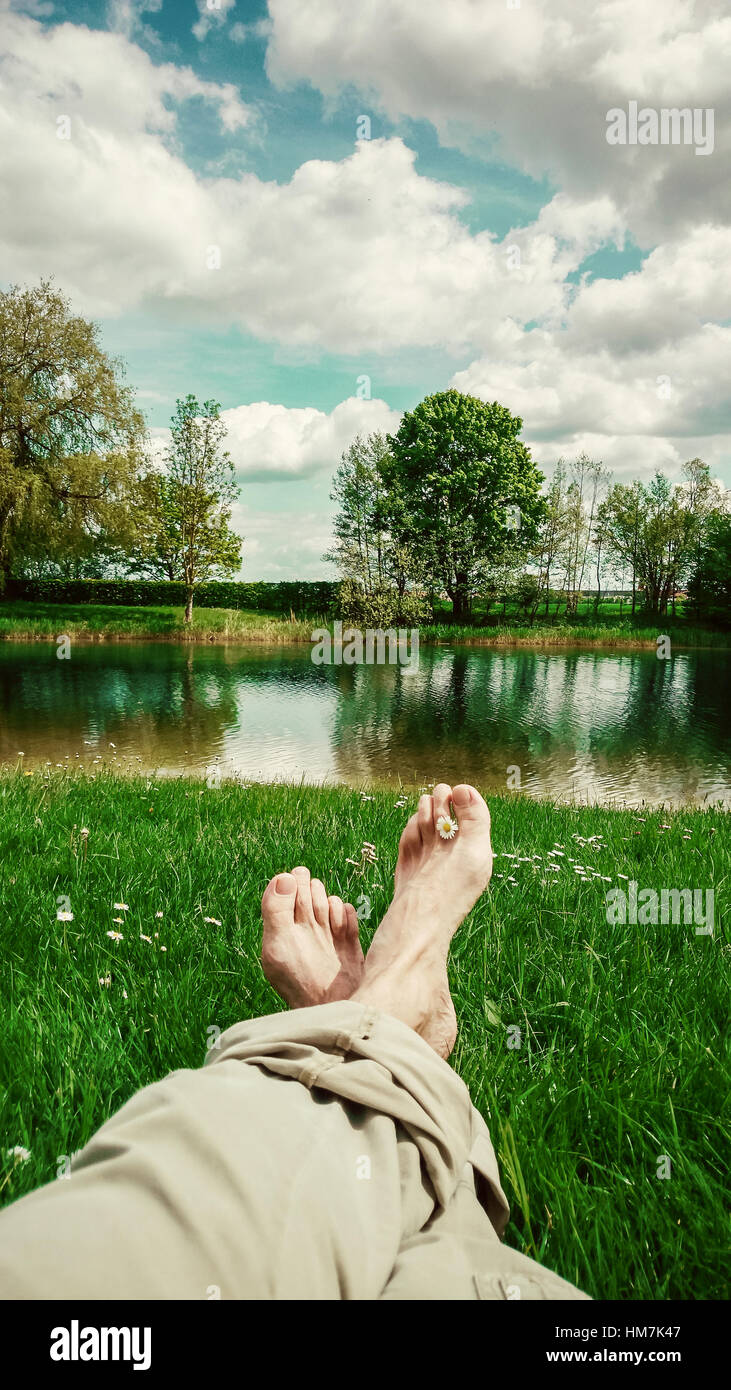 Legs and feet relaxing in front of serene fresh water pond Stock Photo ...