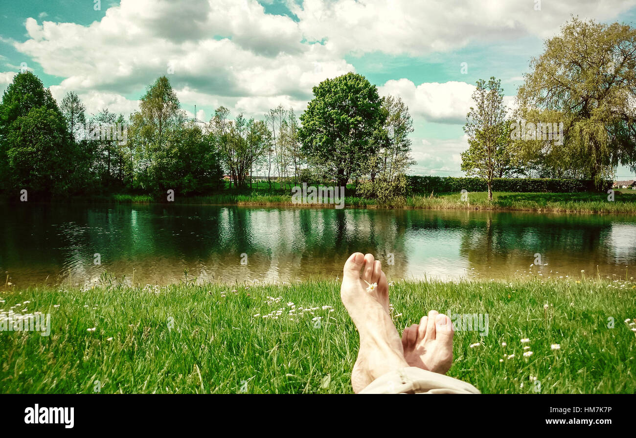 Legs and feet relaxing in front of serene fresh water pond Stock Photo ...