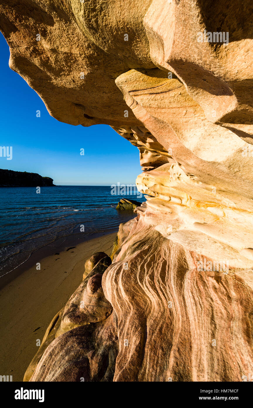 Late afternoon sunlight on waves of sandstone overlooking the ocean ...