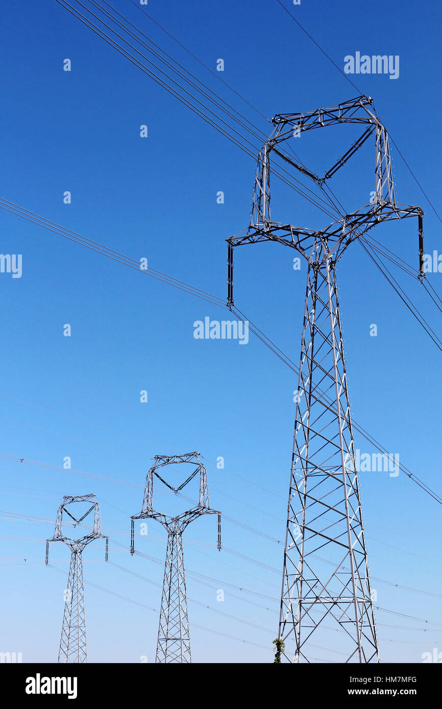three high voltage pylons under blue sky Stock Photo - Alamy