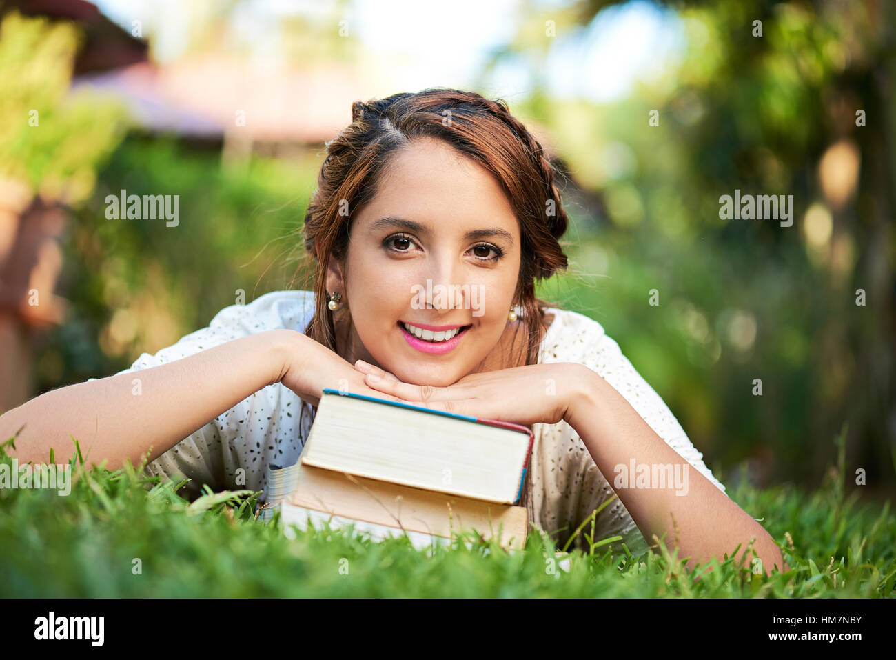 girl lay on top of books on green grass park Stock Photo - Alamy