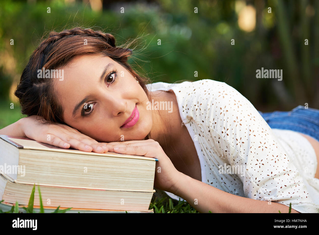 Reading woman laying in a park bench in summer Stock Photo - Alamy