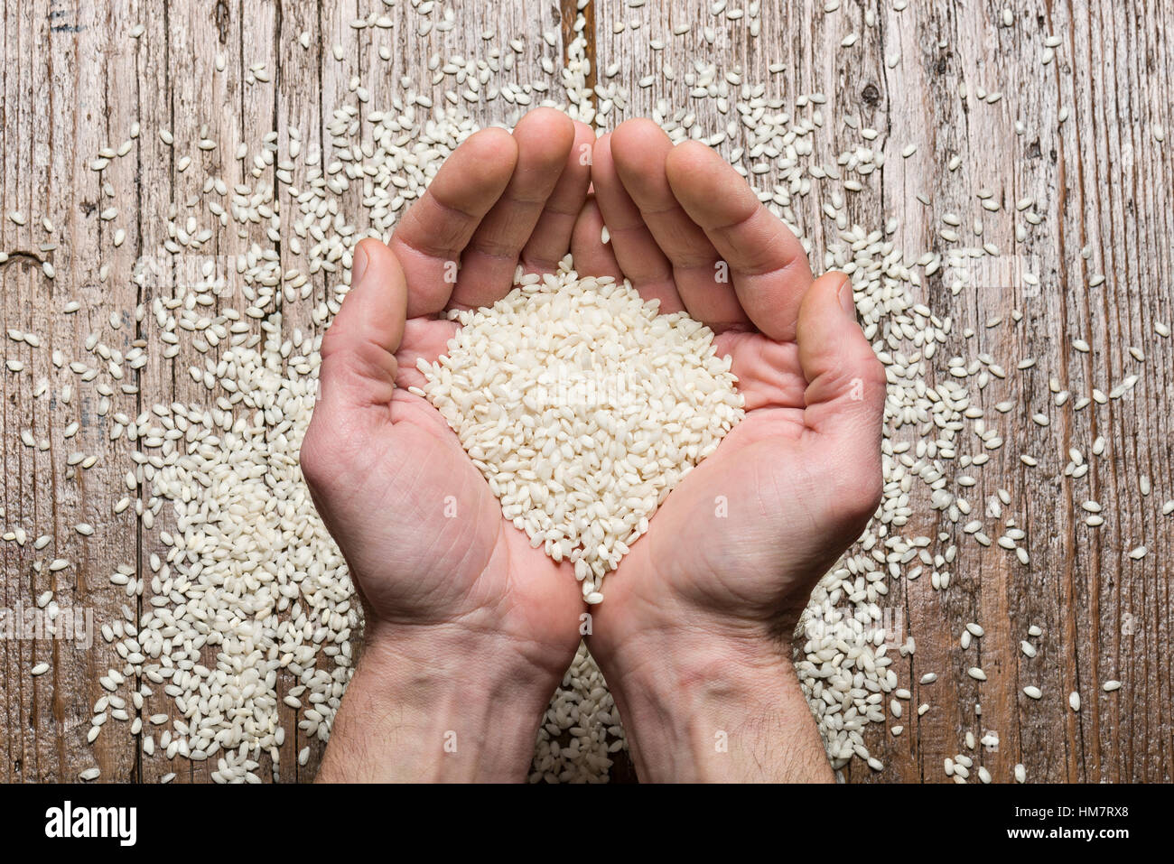 heap of rice in human hands on wooden table Stock Photo - Alamy