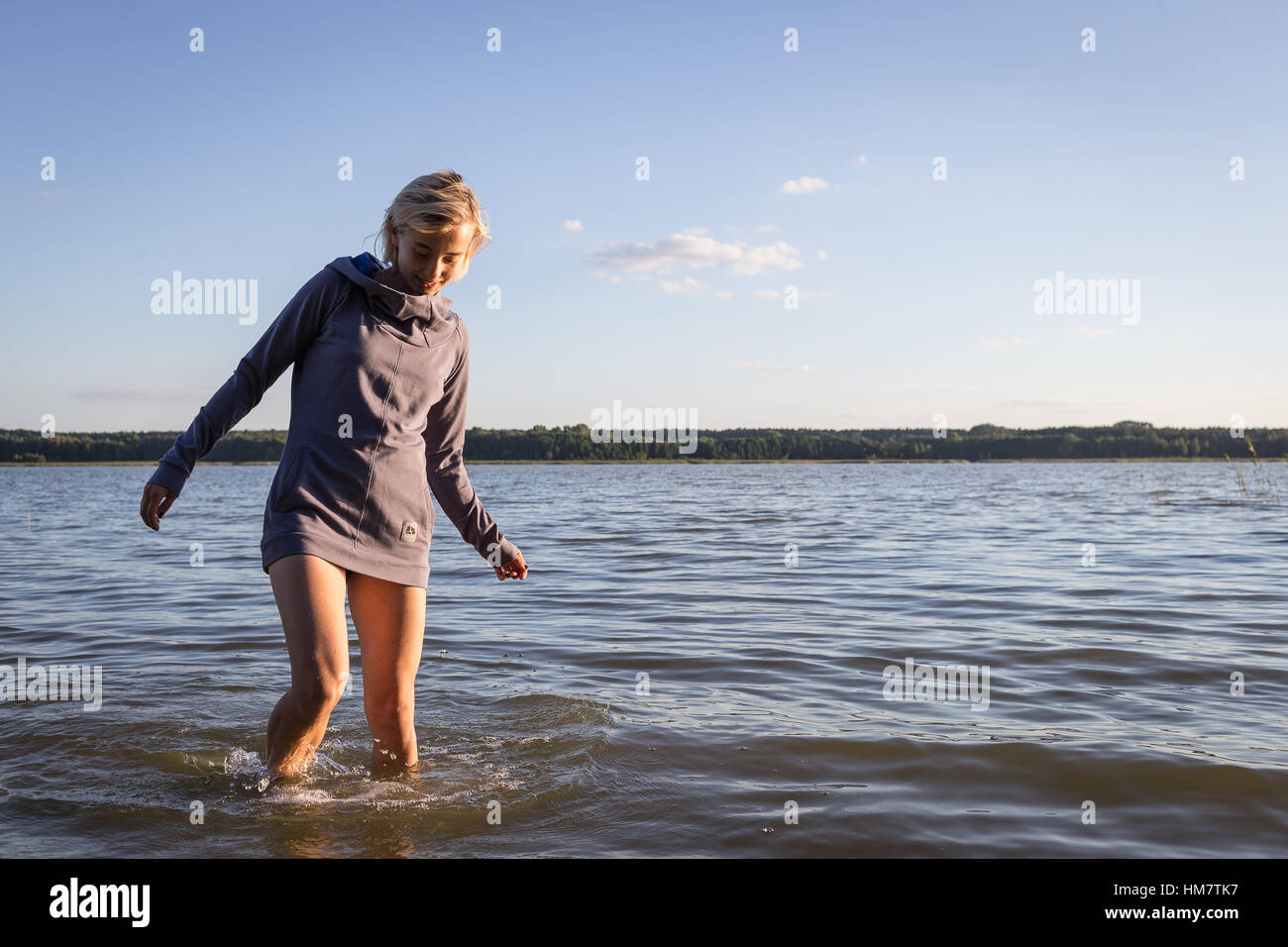 A woman with blond hair wading or paddling through water, lake Stock ...