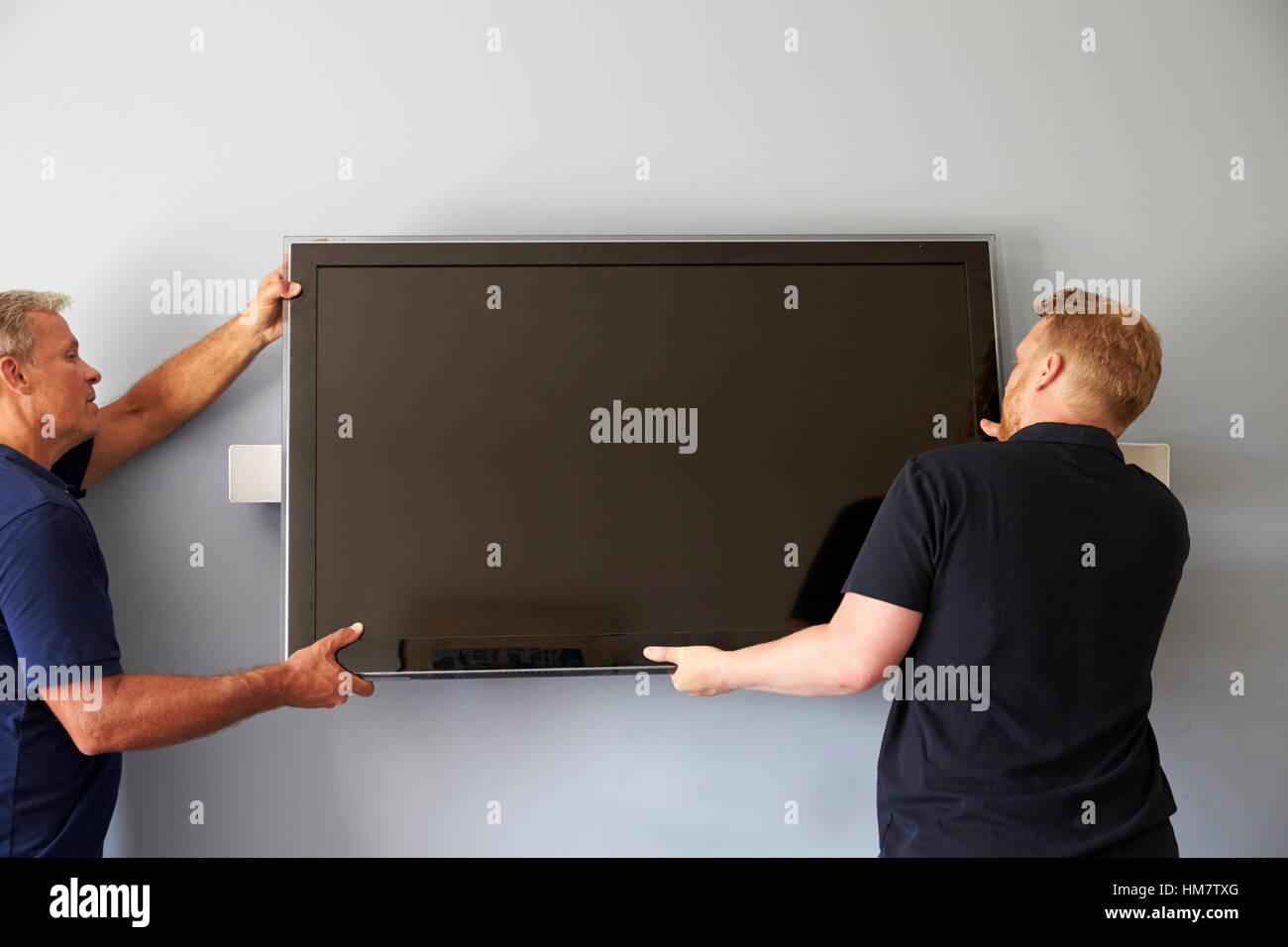 Two Men Fitting Flat Screen Television To Wall Stock Photo - Alamy