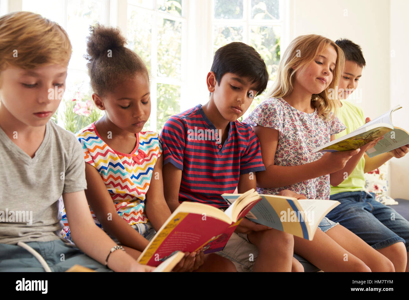 Group Of Multi-Cultural Children Reading On Window Seat Stock Photo - Alamy