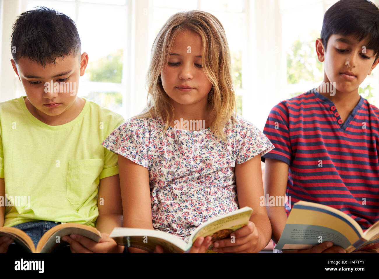 Close Up Of Children Reading On Window Seat Stock Photo - Alamy