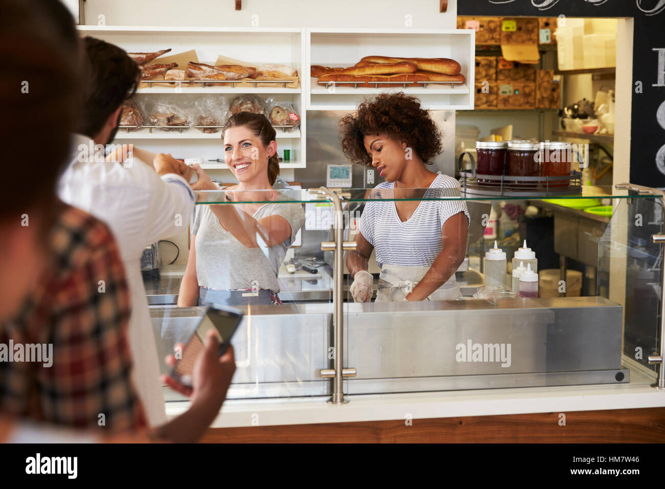 A queue of customers served by two women at a sandwich bar Stock Photo ...