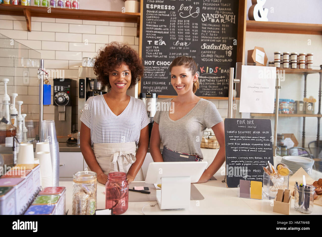 Two women ready to serve behind the counter at a coffee shop Stock ...