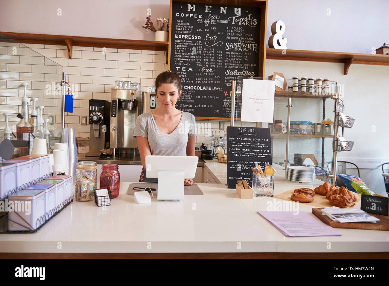 Woman working on the till at the counter of a coffee shop Stock Photo ...