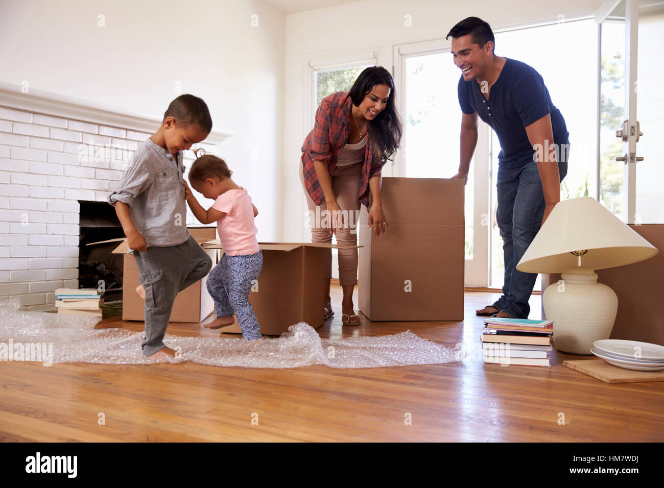 Family Unpacking Boxes In New Home On Moving Day Stock Photo - Alamy